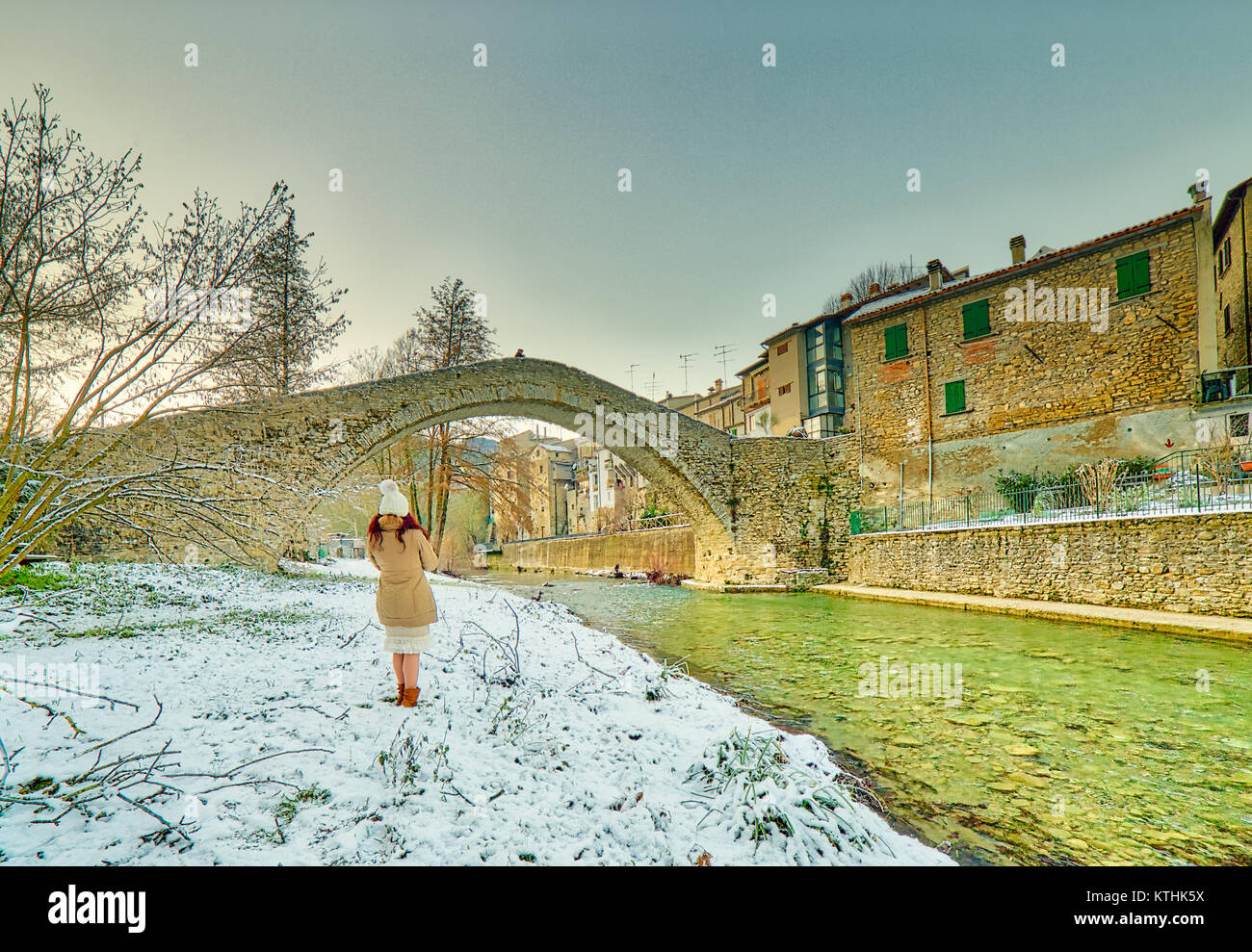 woman near Ancient medieval donkey-back bridge with a unique arch in a ...