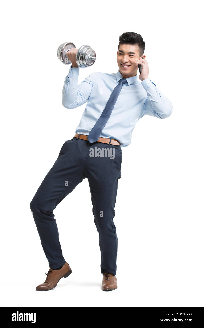 Young businessman talking on the phone while lifting weights Stock ...