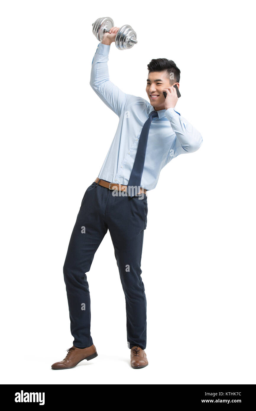 Young businessman talking on the phone while lifting weights Stock ...