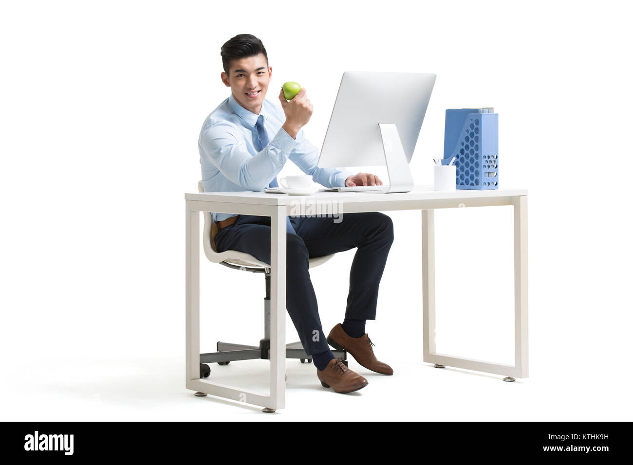 Young businessman working with computer in office holding apple Stock ...