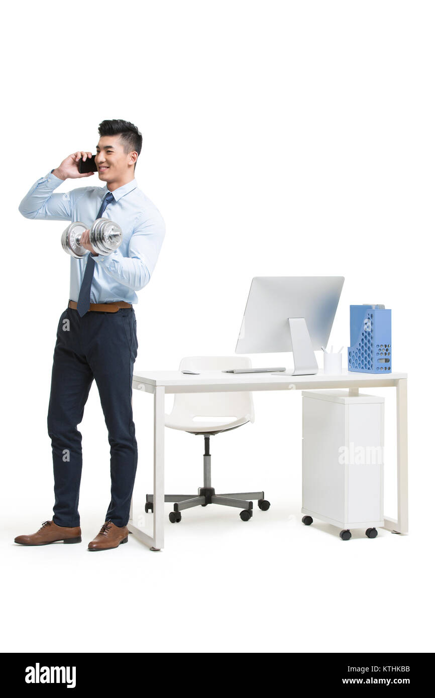 Young businessman talking on the phone while lifting weights Stock ...