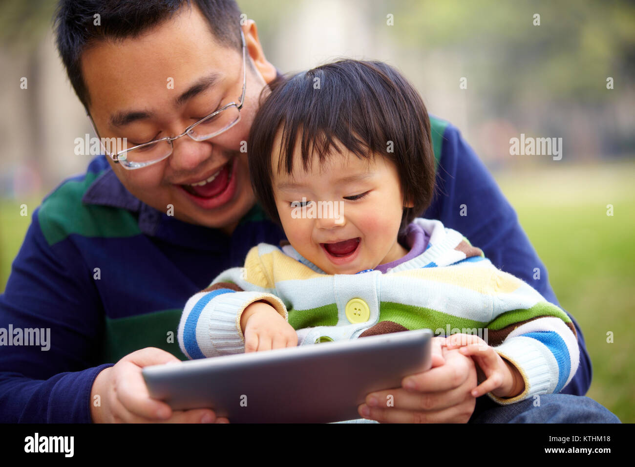 happy asian father using tablet with his little girl outdoor in the ...