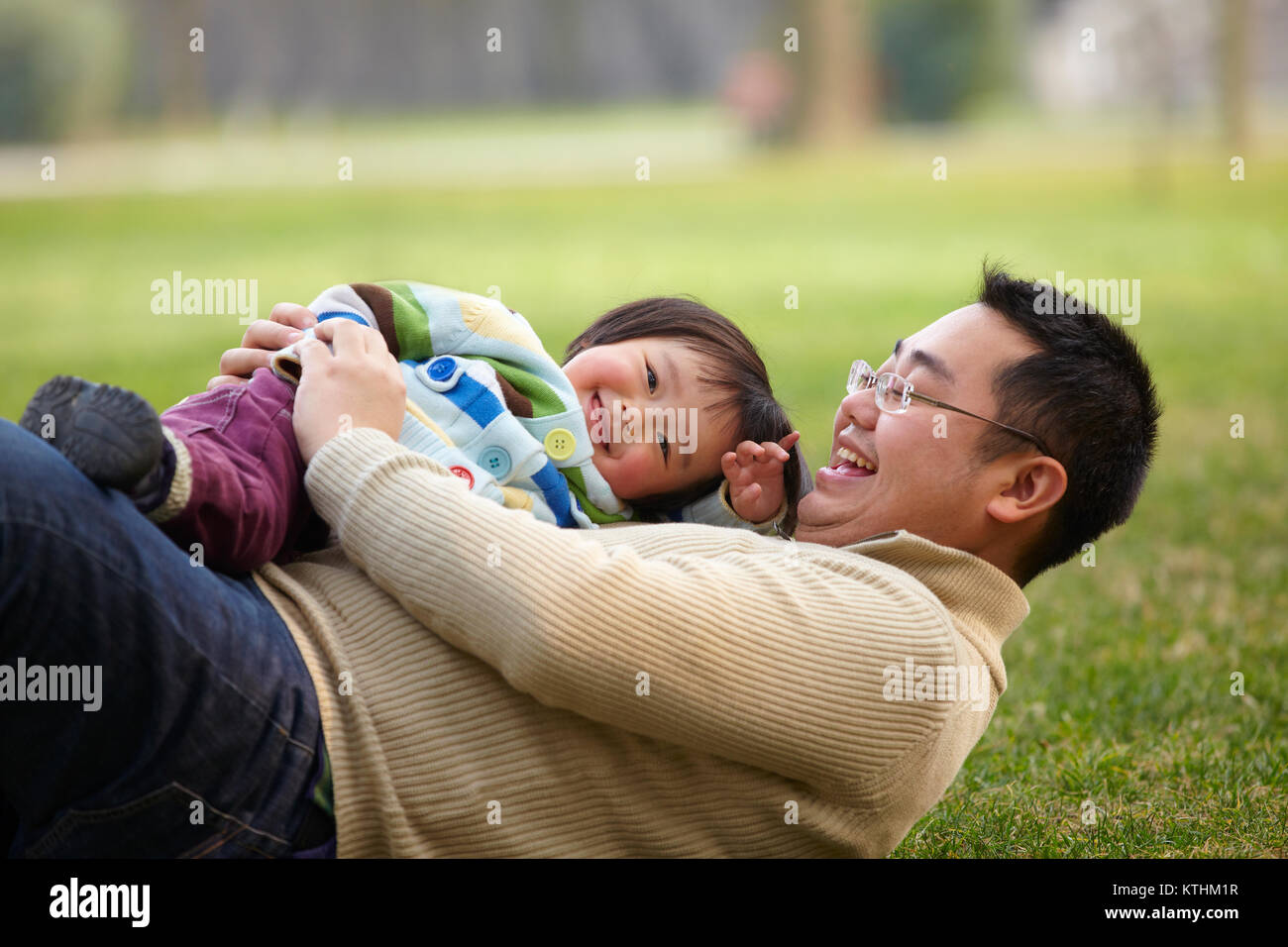 happy asian father playing with his little girl outdoor in the park ...