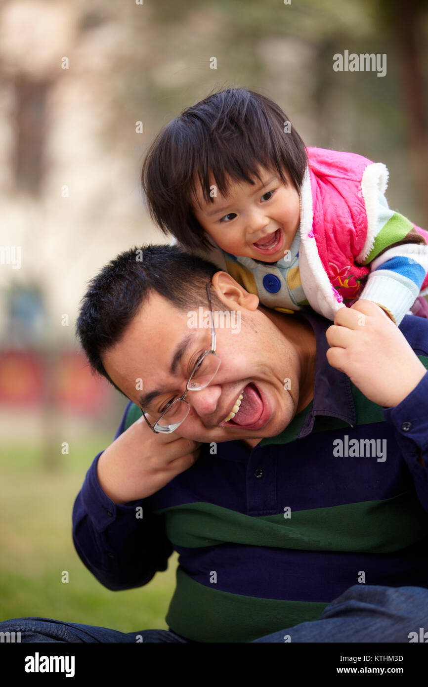 happy asian father playing with his little girl outdoor in the park ...
