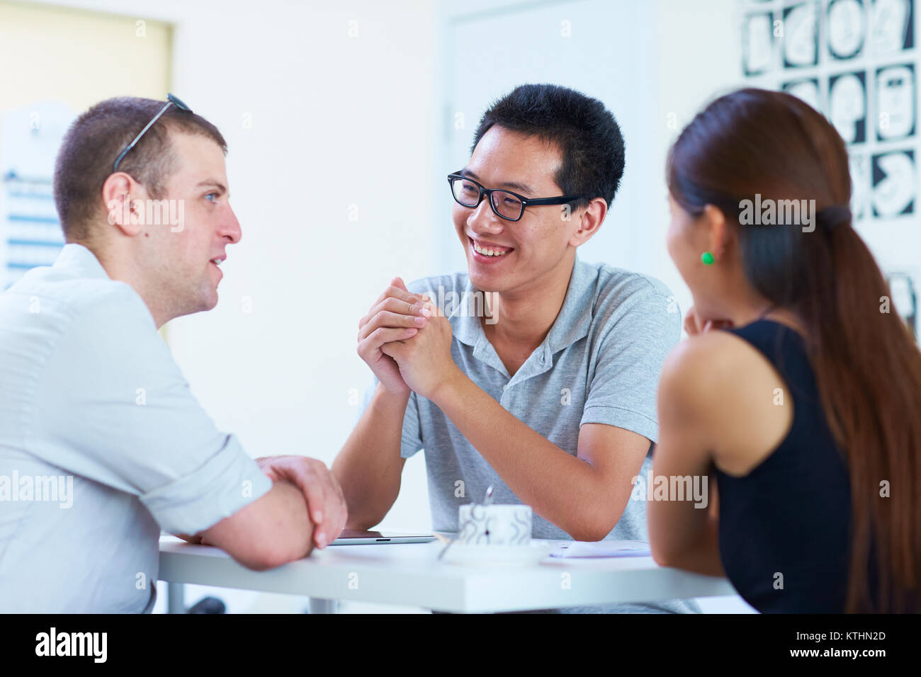 two asian business people having meeting with one white businessman ...
