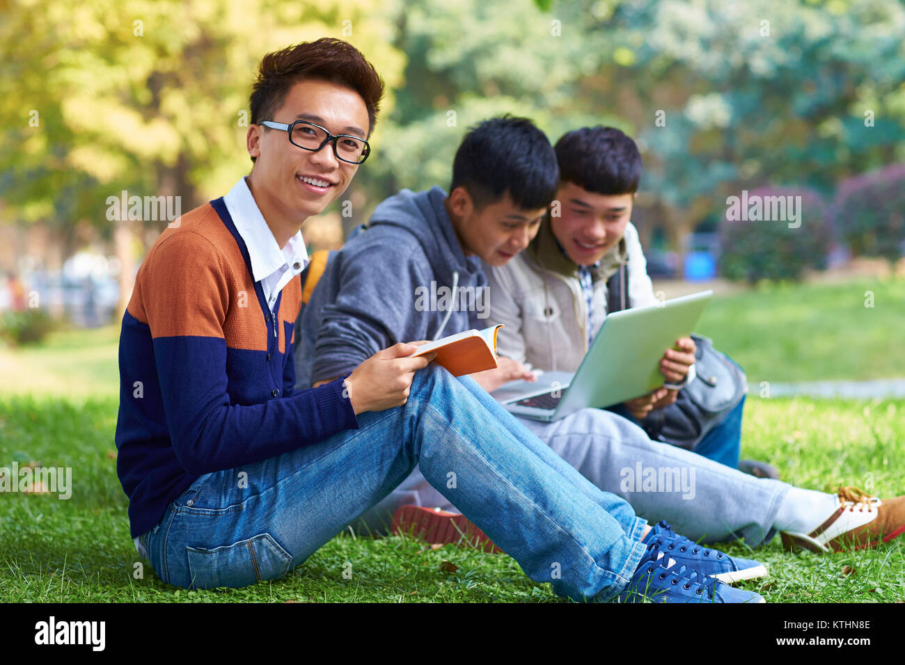 Group of Happy Chinese College Students Reading Book on Lawn in Campus ...
