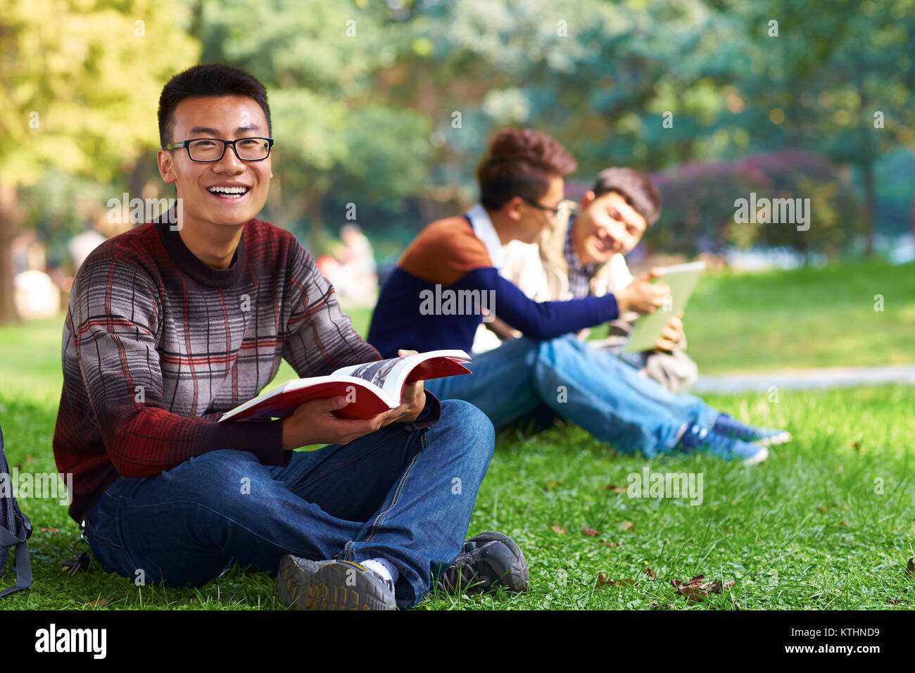 Group of Happy Chinese College Students Reading Book on Lawn in Campus ...