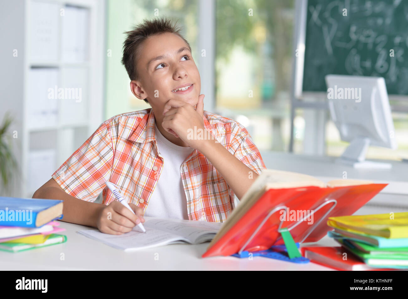 Thoughtful schoolboy doing homework Stock Photo - Alamy