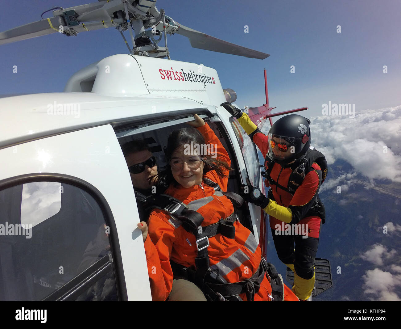 This tandem skydiving team is climbing out of the helicopter and are ...