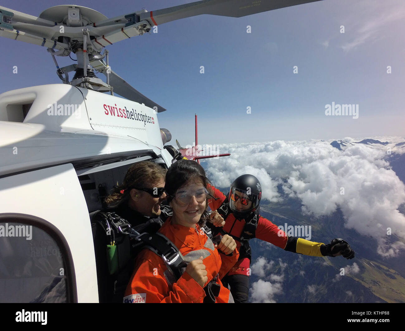 This tandem skydiving team is climbing out of the helicopter and are ...
