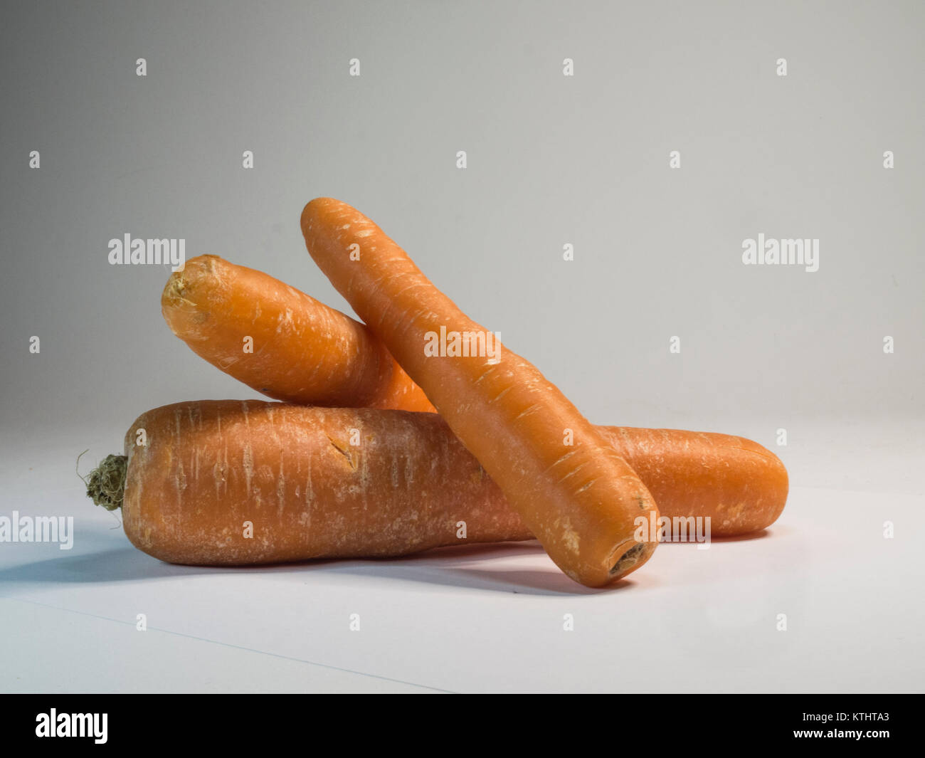 Three carrots on white background Stock Photo - Alamy