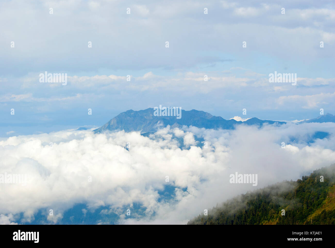 mountain landscape with a blue ridge and clouds in the valley deep down ...