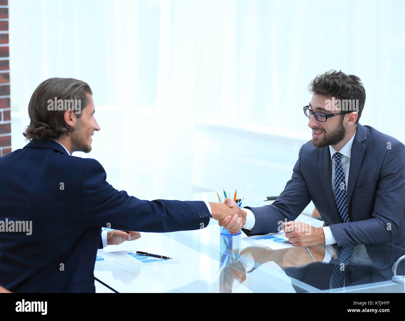handshake of business partners sitting at their Desk Stock Photo - Alamy