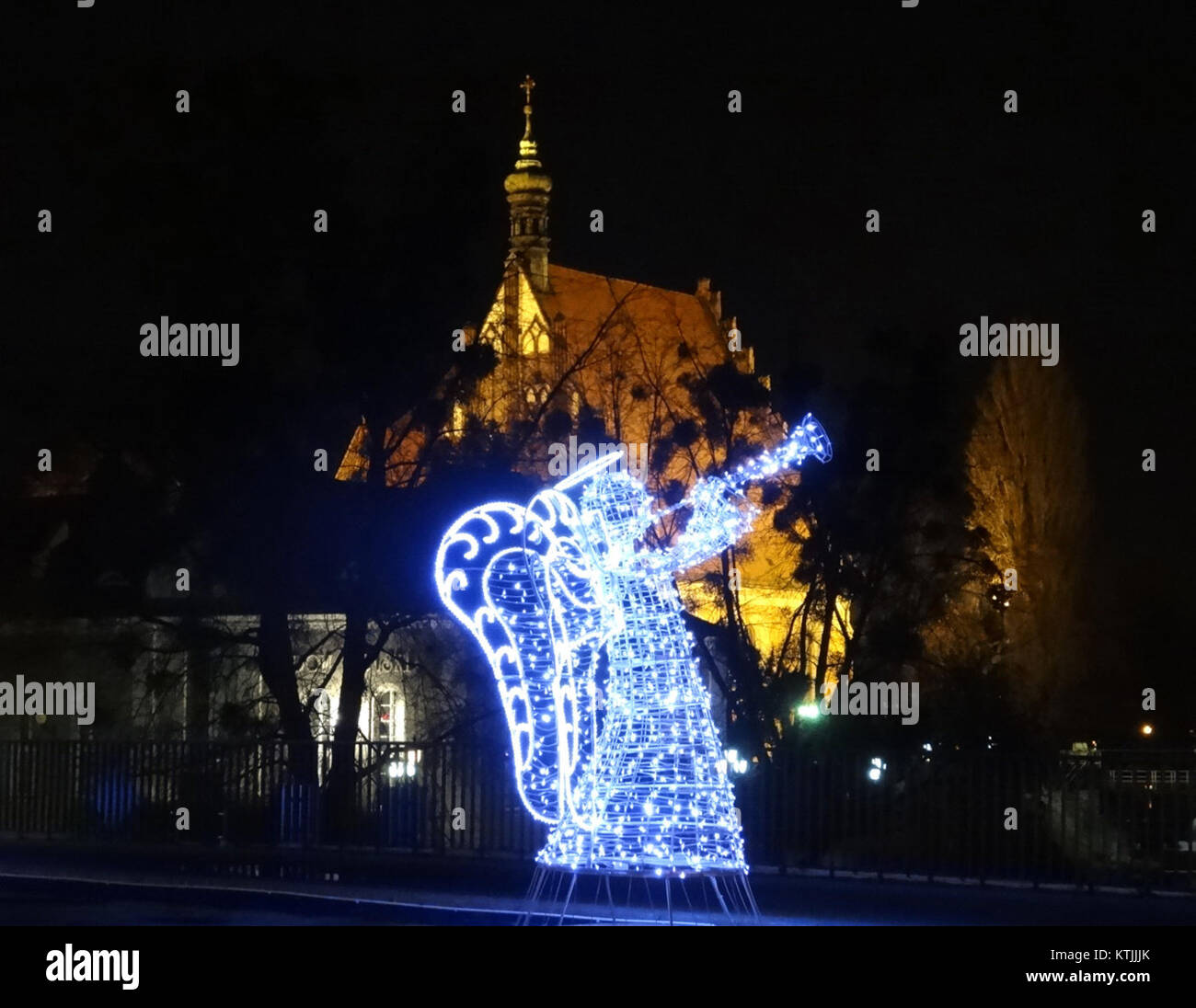 This image depicts a nighttime view of a cathedral and angel statue ...