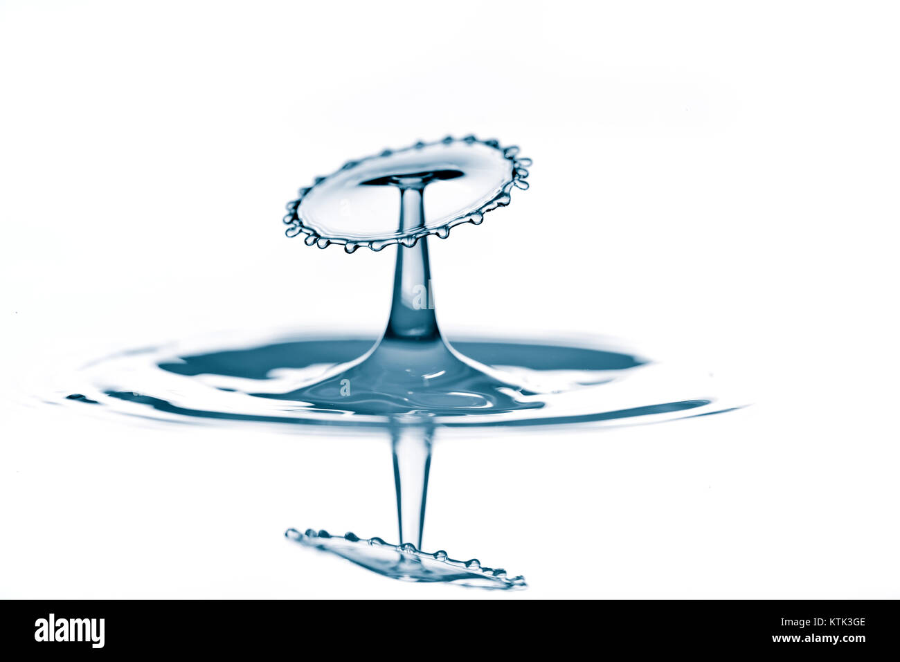 Splash and crown on rippled blue liquid or water surface . Water splash ...