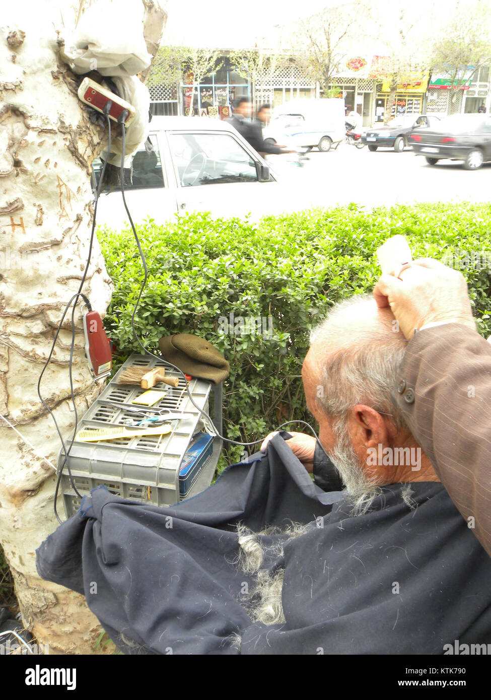A barber is seen working on the sidewalk of a street in Nishapur, Iran ...