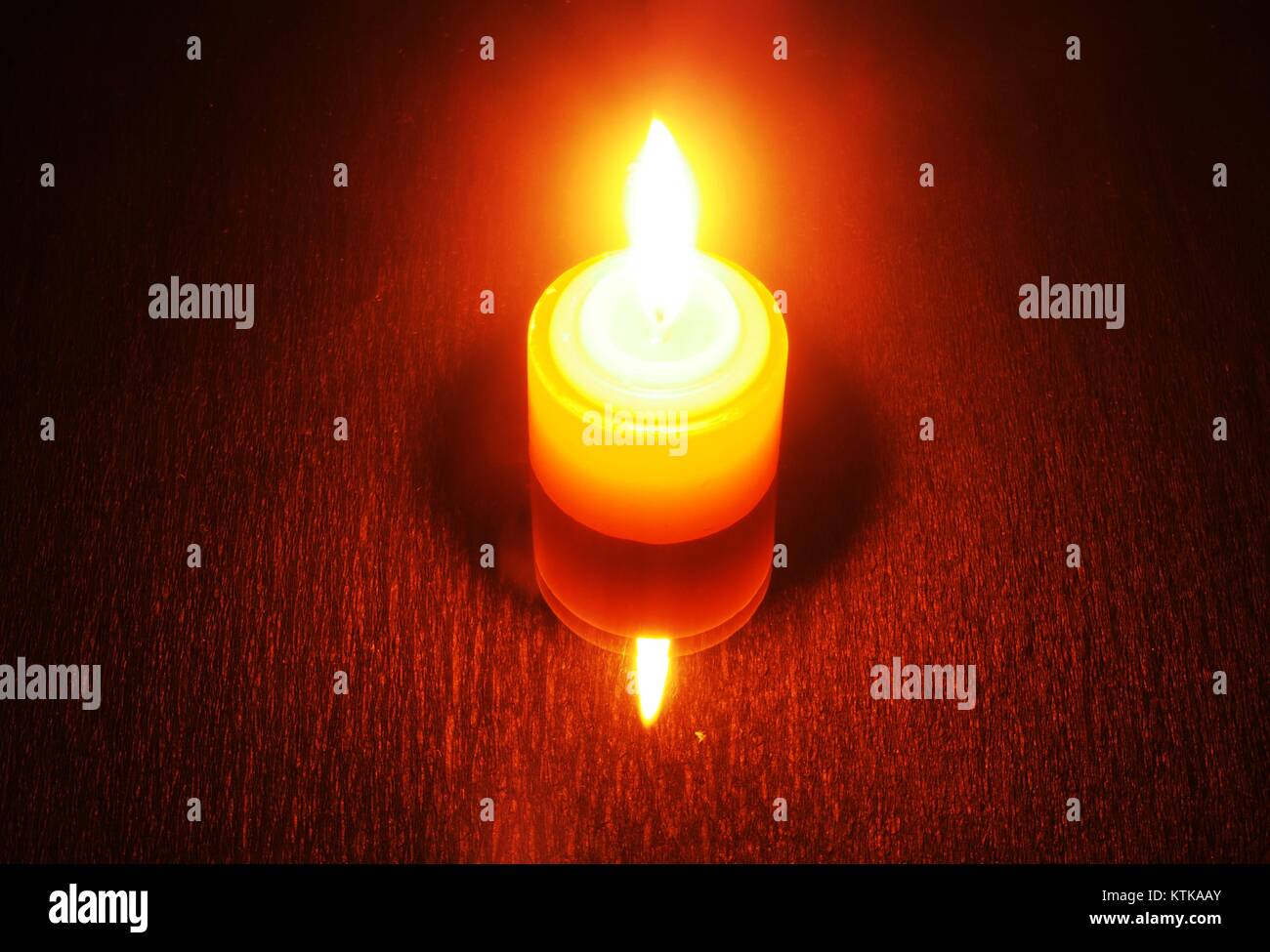 Burning candle on a reflective table. Visible candle and its reflection ...
