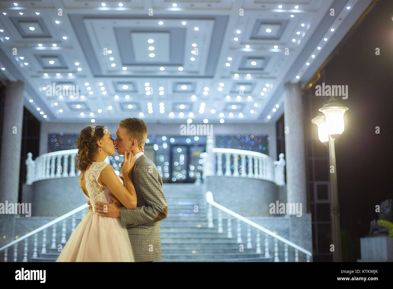The bride and groom stand on the beautiful porch of the hotel at night ...