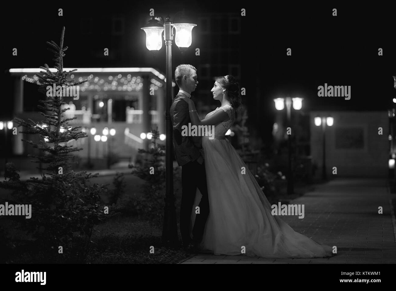 The bride and groom stand on the beautiful porch of the hotel at night ...