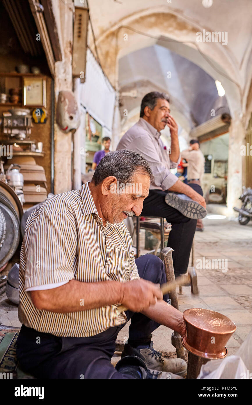 Yazd, Iran - April 22, 2017: The old copper-maker makes a copper pot in ...