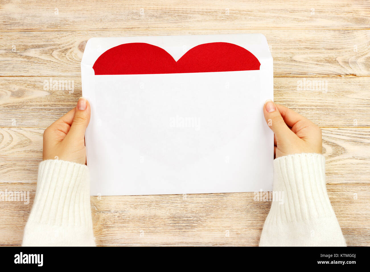 A female woman hand hold open a envelope and post card on the wood desk ...