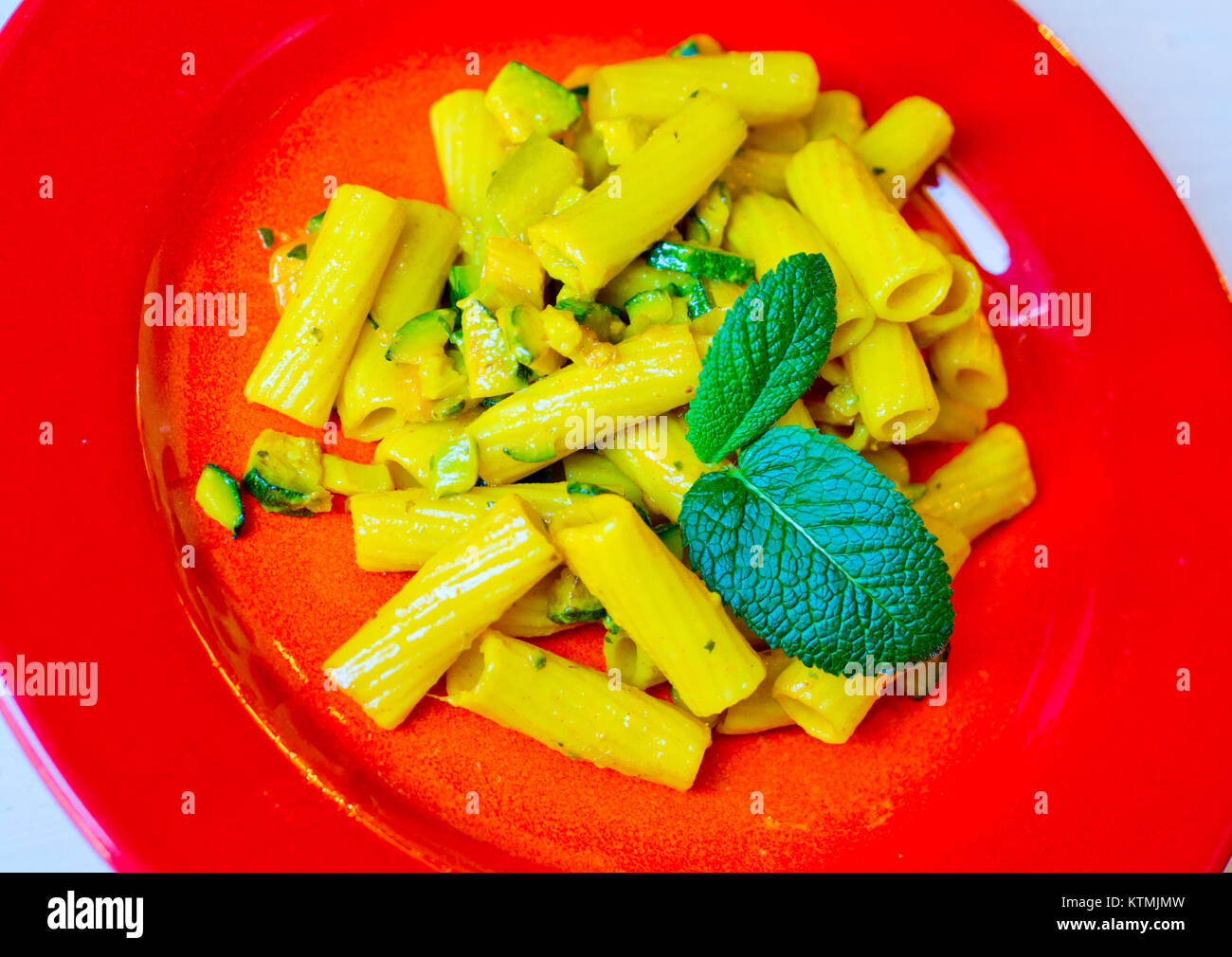 pasta dish topped with a bright yellow colored sauce with vegetables ...