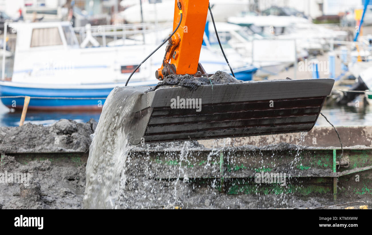 Excavator shovel digging in sand from water. Building construction ...