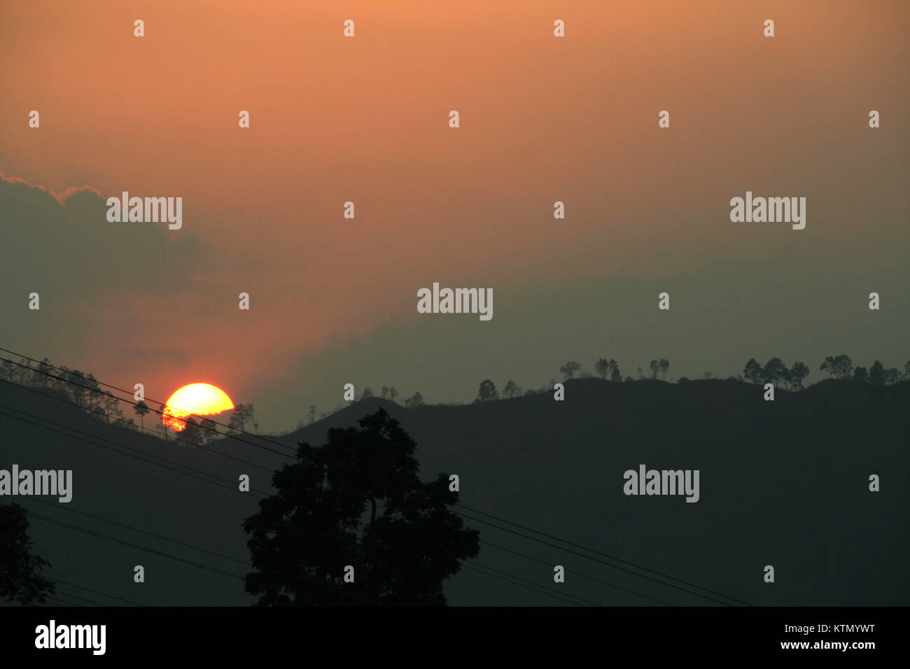 Golden yellow disc of setting sun behind mountain Stock Photo - Alamy