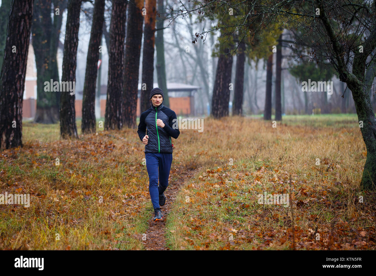 Young running man in fall park. Jogging in cold and misty weather Stock ...