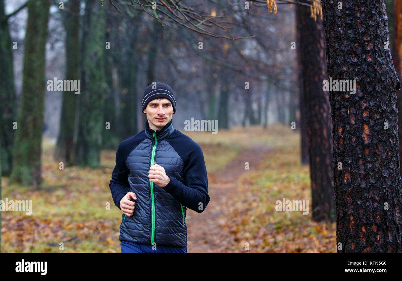 Young running man in fall park. Jogging in cold and misty weather Stock ...