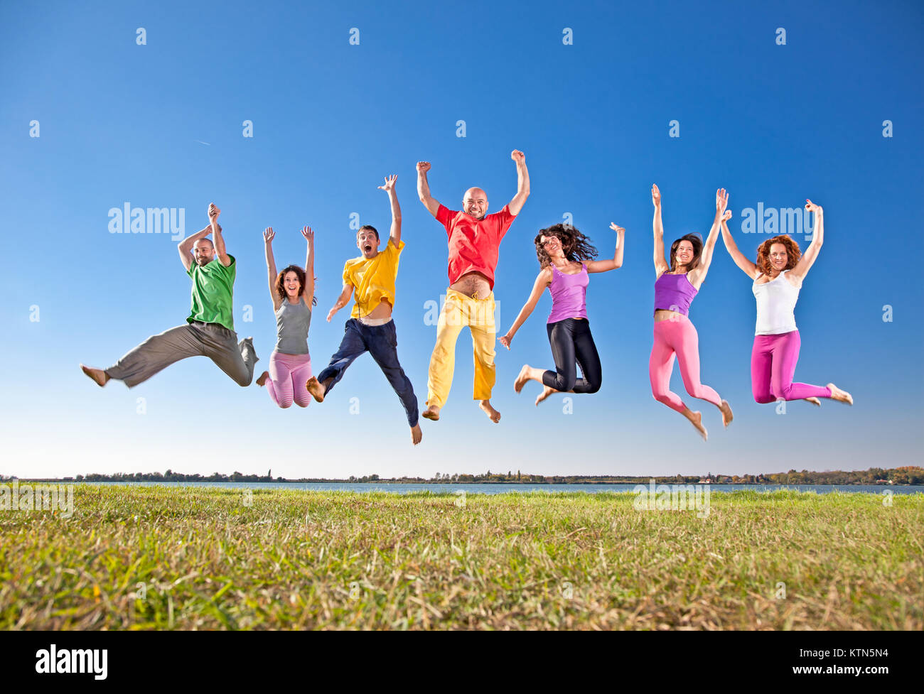 Happy smiling group of jumping people on banch of lake Stock Photo - Alamy