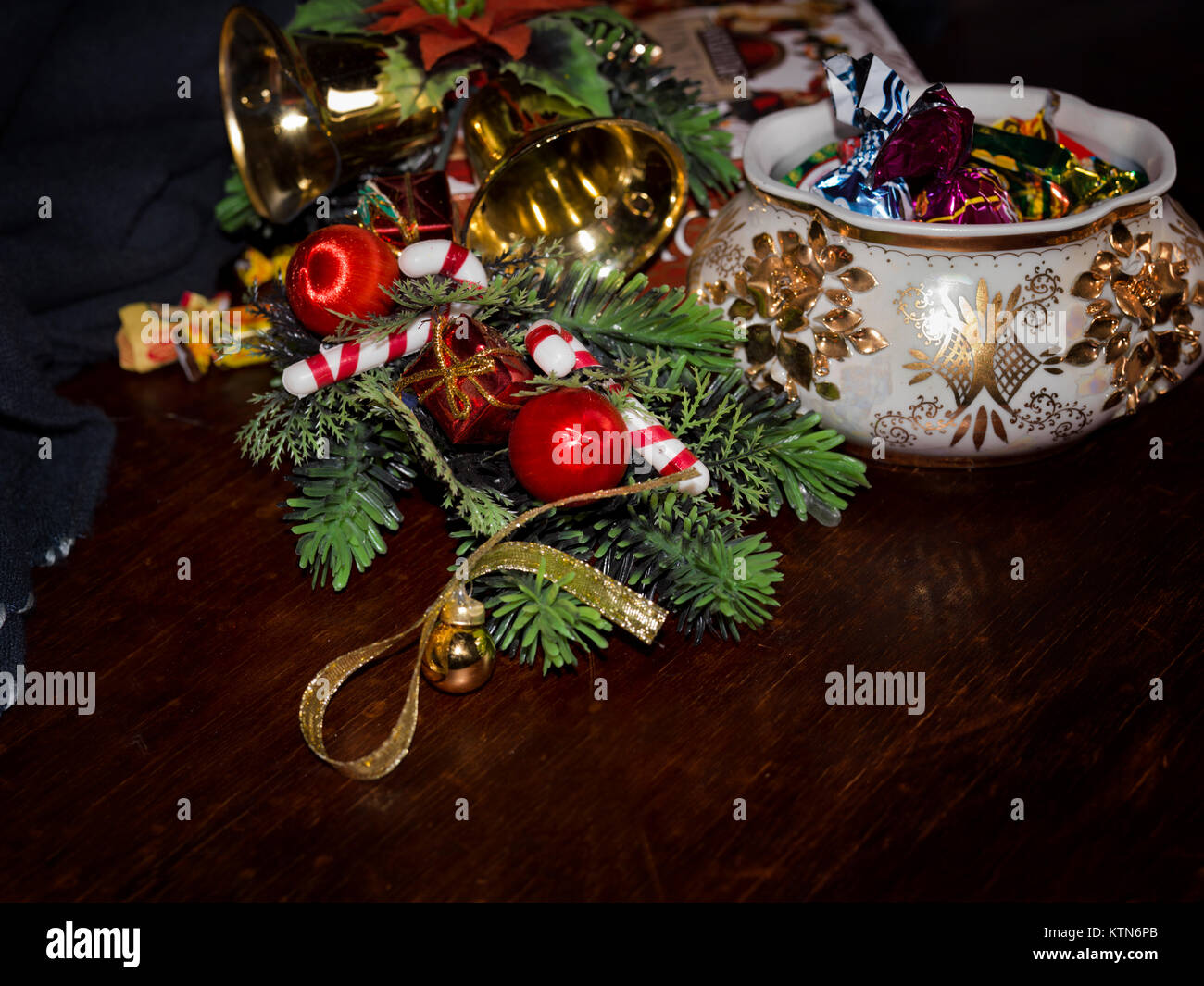Evergreen tree branch with bells laid on the table with vase of sweets ...