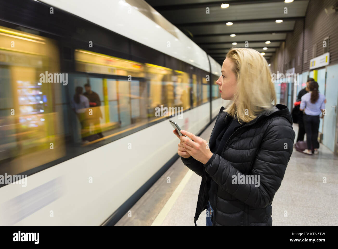 Woman with a cell phone waiting for metro Stock Photo - Alamy