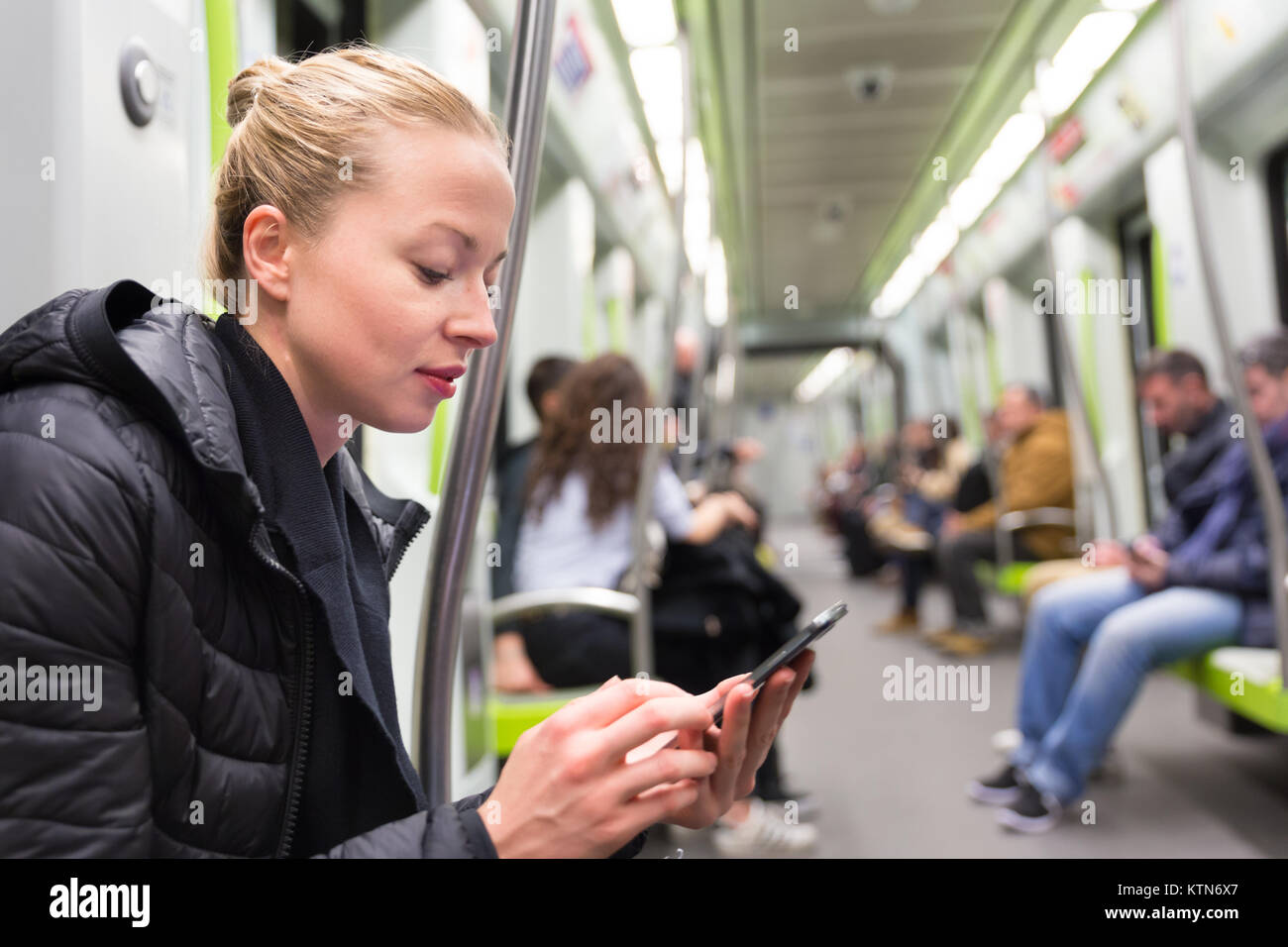 Young girl reading from mobile phone screen in metro Stock Photo - Alamy