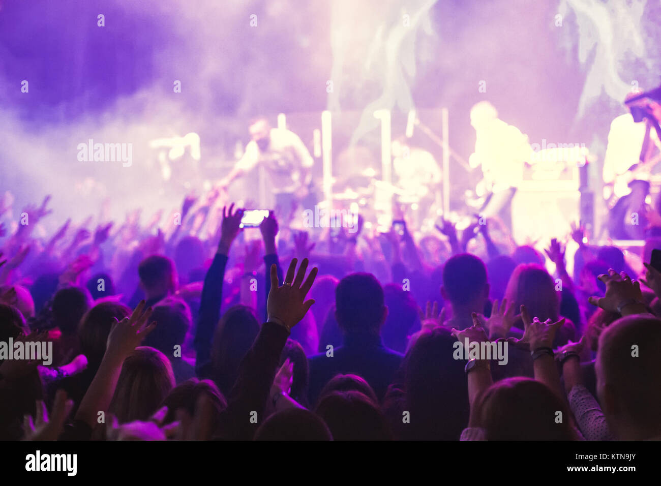 A crowd of spectators at a concert in a small concert club. Applaud and ...