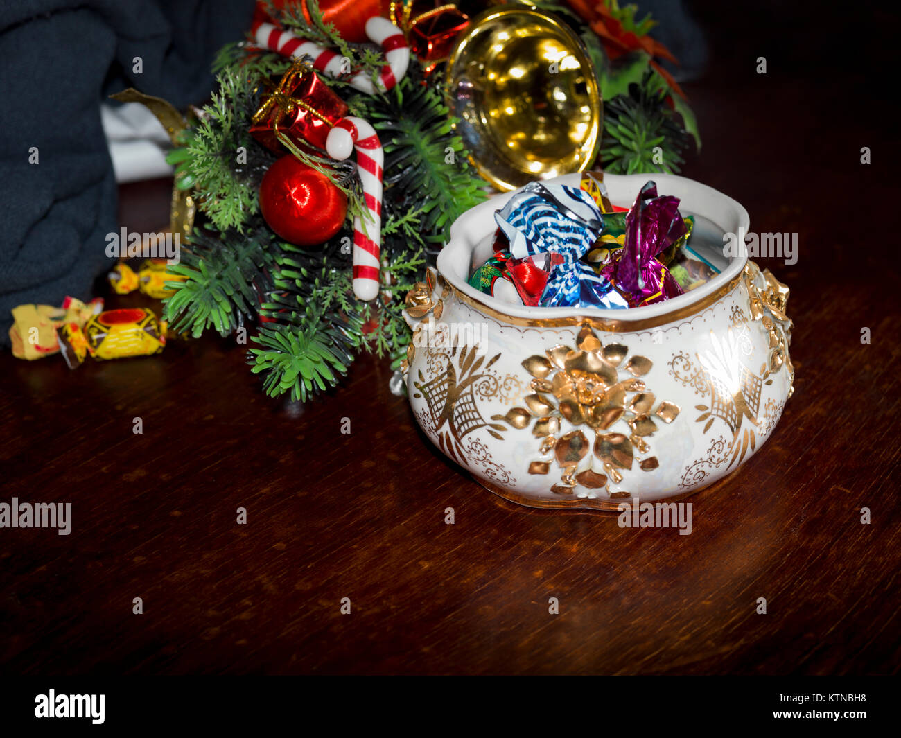 A vase of sweets, evergreen tree branch, bells laid on the table and ...