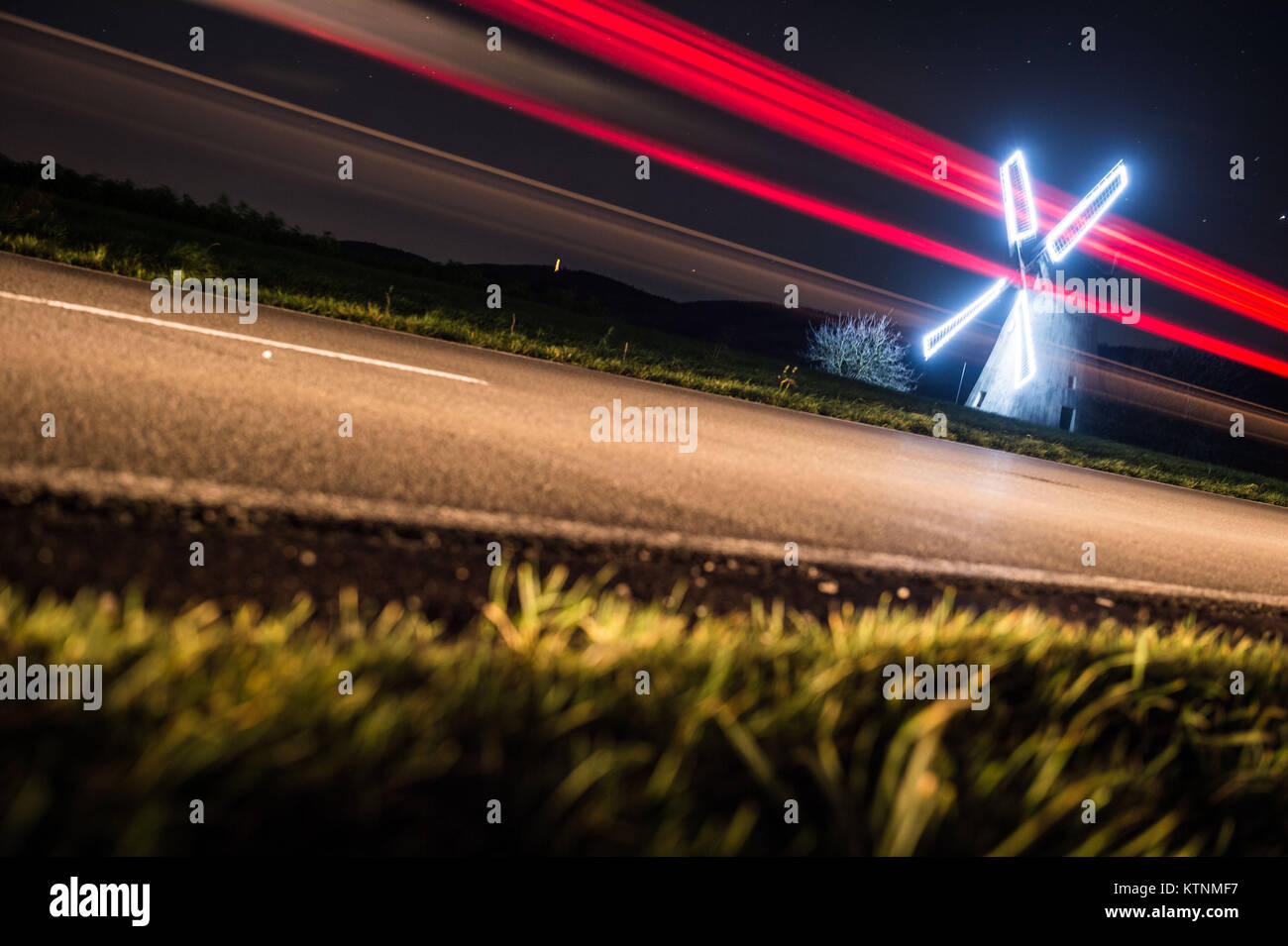 Huellhorst, Germany. 26th Dec, 2017. A car passes a glowing windmill ...