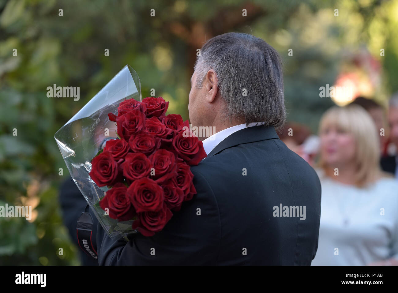 Back view of man in suit holding bunch of beautiful red roses on his ...