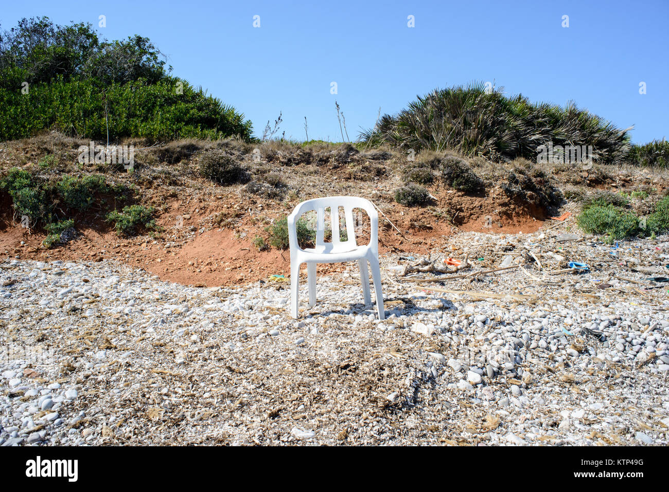 Front view of an abandoned plastic white chair as a waste on a beach in ...