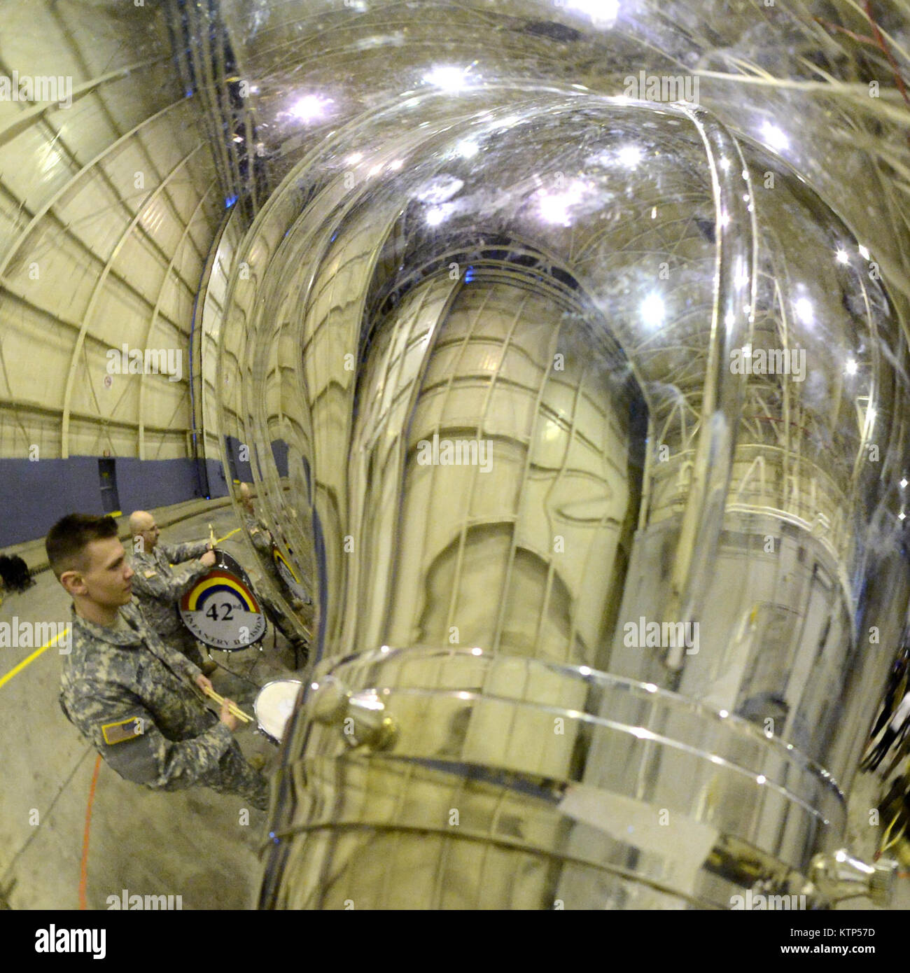 In a reflected image off of a tuba, U.S. Army Soldiers, with the 42nd ...