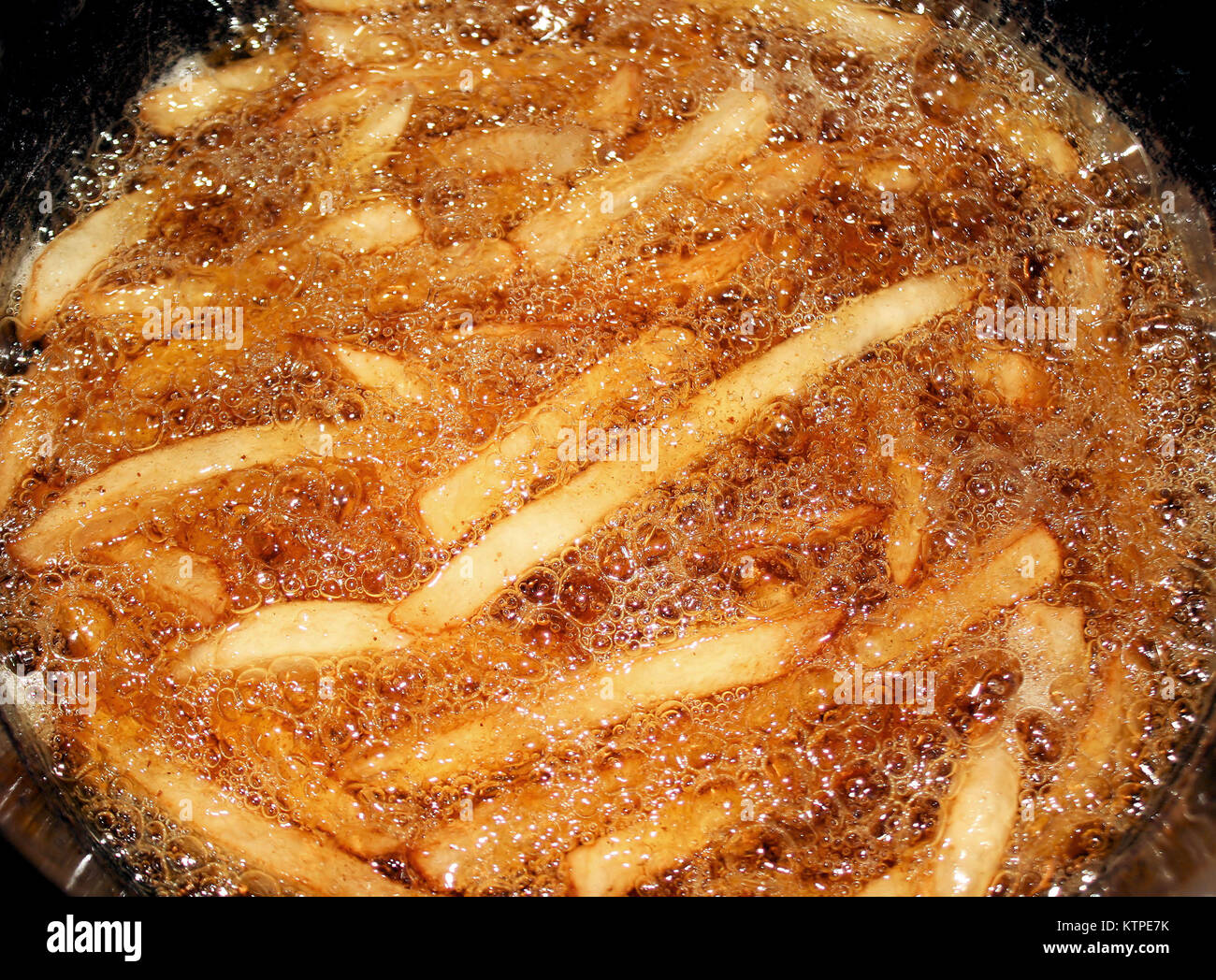 French fries cooking and bubbling in a deep fryer filled with oil Stock ...