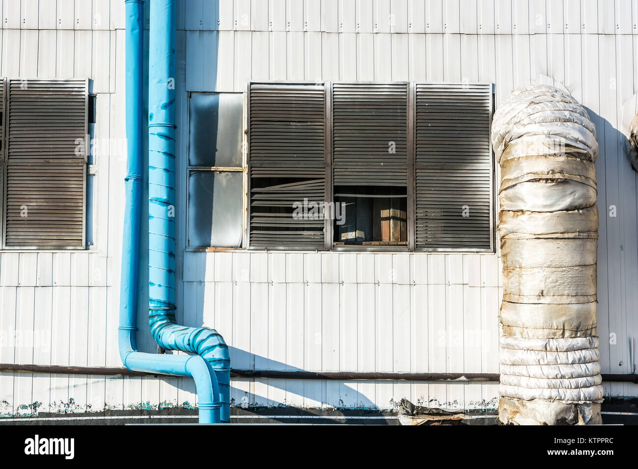 Close up wall of factory building and blue metal pipes Stock Photo - Alamy