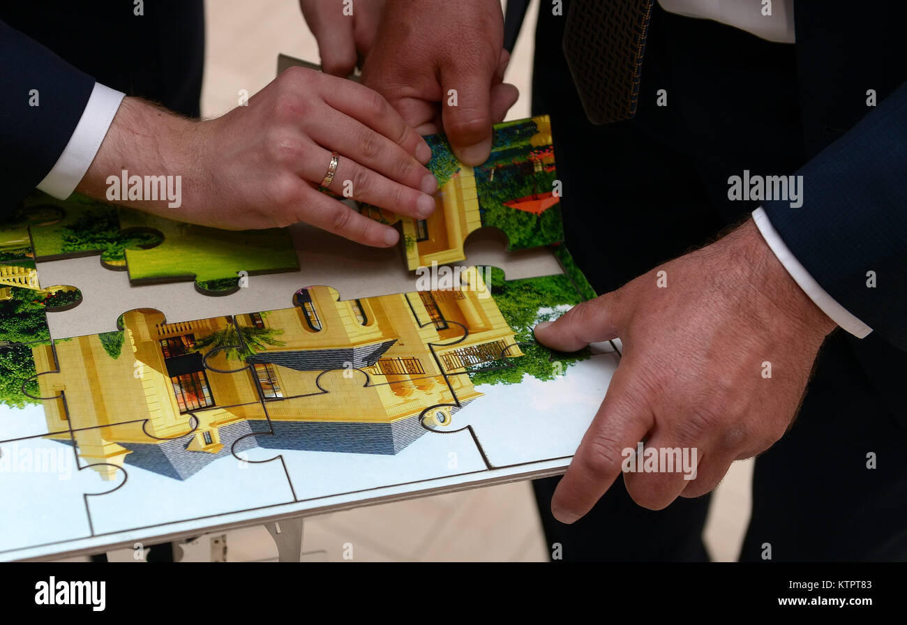 Close up hands of men putting together puzzle picture of house Stock ...