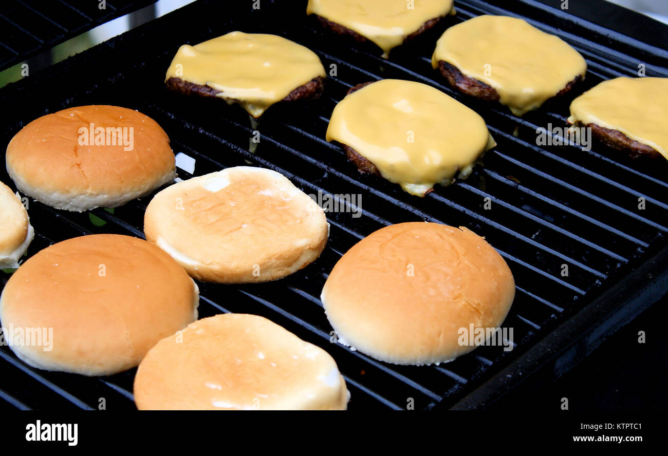 Hamburger patties with processed cheese slices cooking on an outdoor ...
