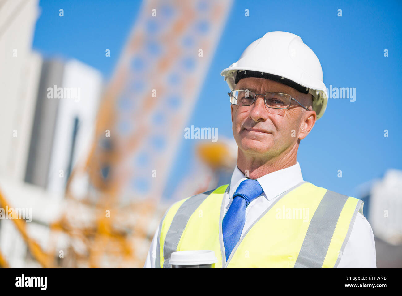 Senior foreman in glasses doing his job at building area on sunny day ...