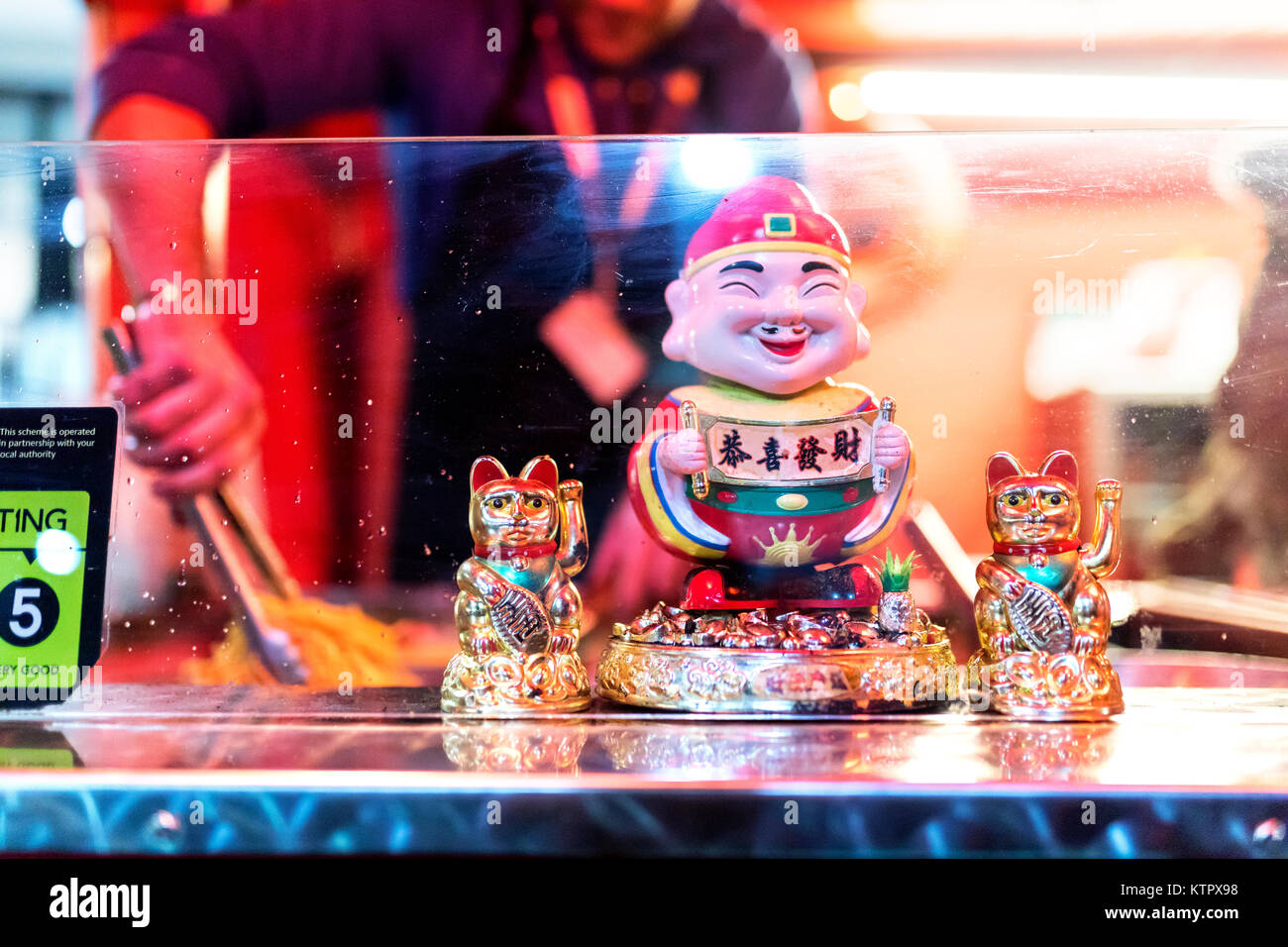 Ornamental statue of an Oriental smiling emperor reading a scroll ...