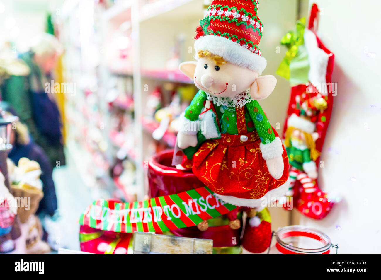 Handcrafted fabric Christmas elf toy with woollen hat hanging in a shop ...