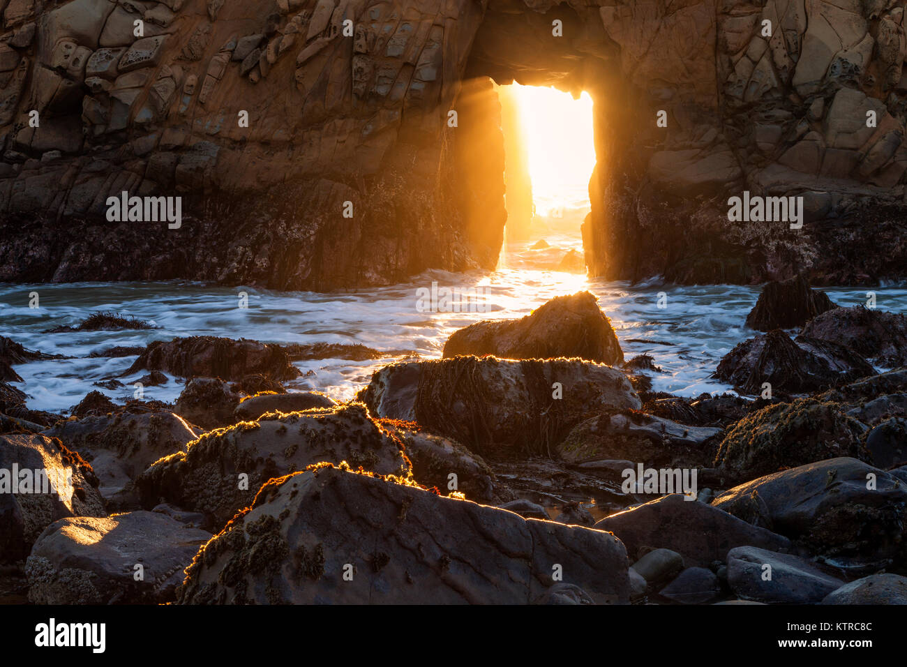 Sunlight and surf stream through Keyhole Arch at Pfeiffer Beach along ...