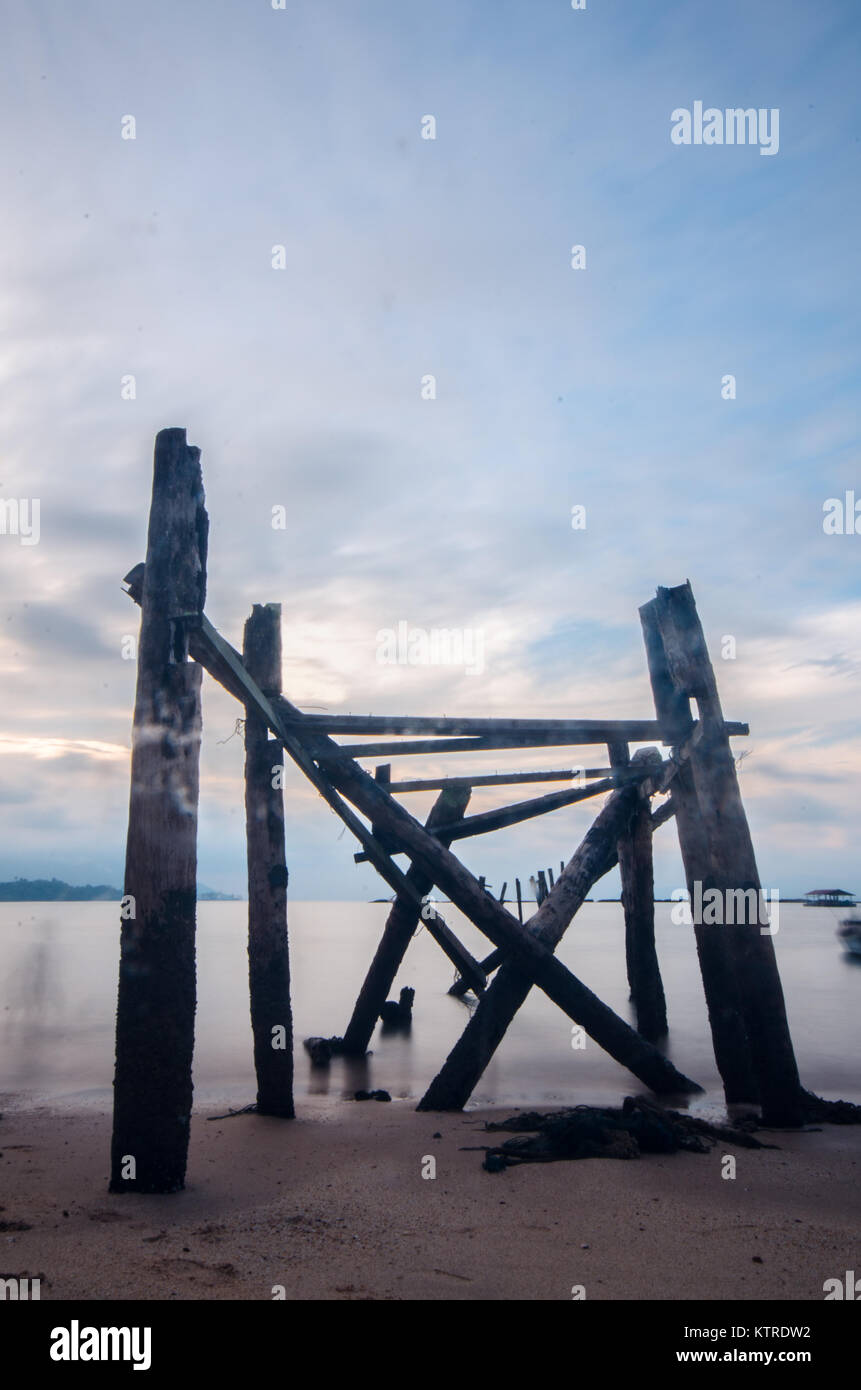 Cloudy day at old and damage boat jetty at Black Sand Beach in Langkawi ...