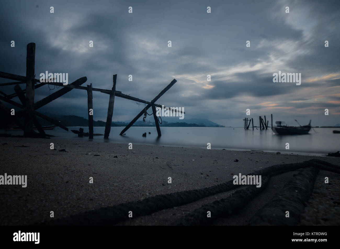 Cloudy day at old and damage boat jetty at Black Sand Beach in Langkawi ...